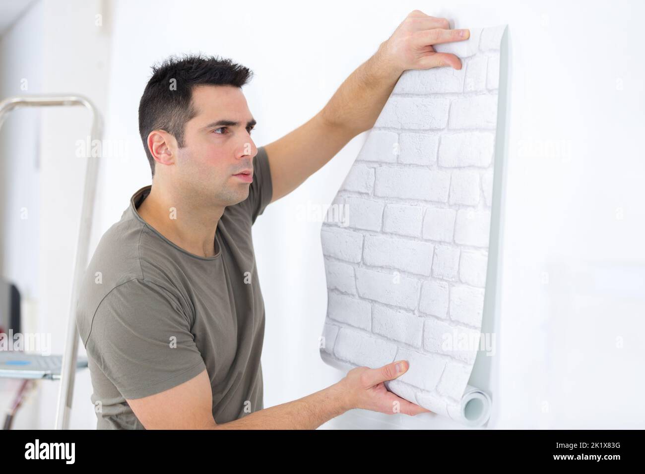 handyman putting up wallpaper on the white walls Stock Photo - Alamy