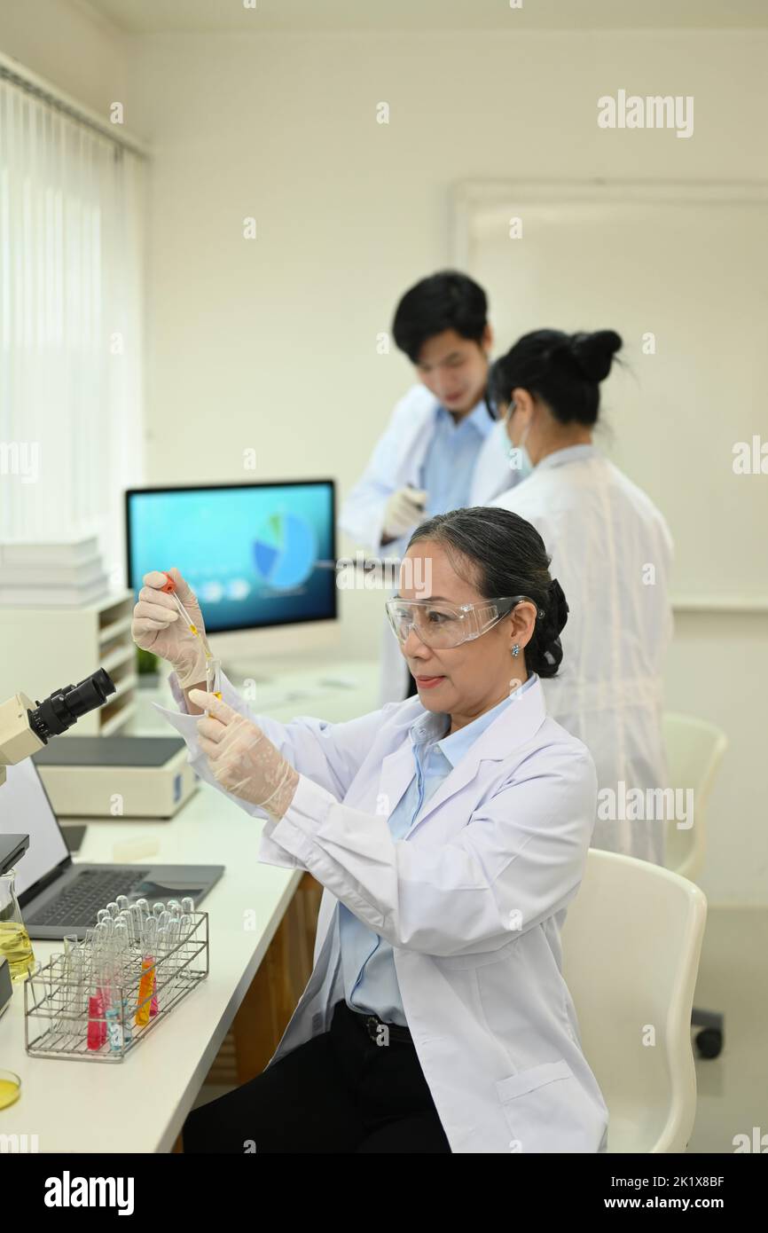 Professional scientists wearing white coats conducting experiment in ...