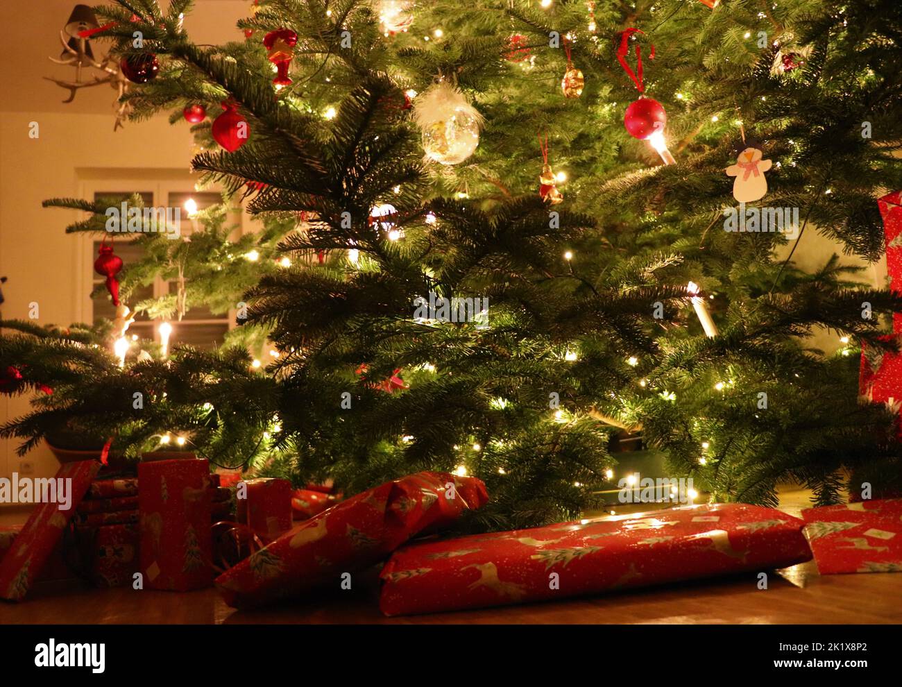 A closeup of a Christmas tree decorated with balls and lights, and red ...