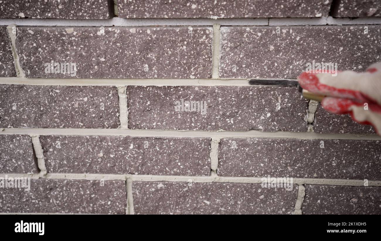 Processing of seams on brickwork. Slow motion closeup of worker filling ...