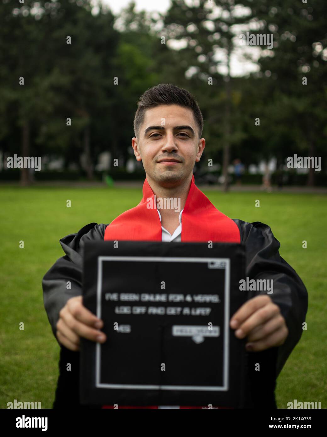 A vertical of a Caucasian young guy smiling and holding his cap on his ...