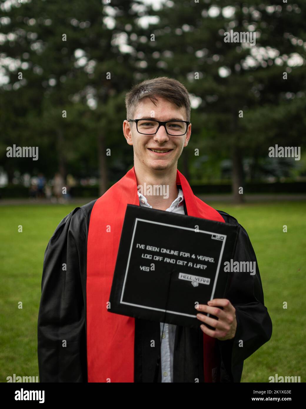 A vertical of a Caucasian young guy smiling and holding his cap on his ...
