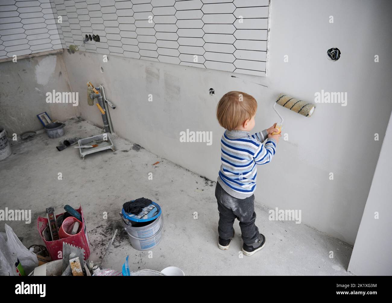 Side view of cute blond boy doing repair at home with special brush and ...