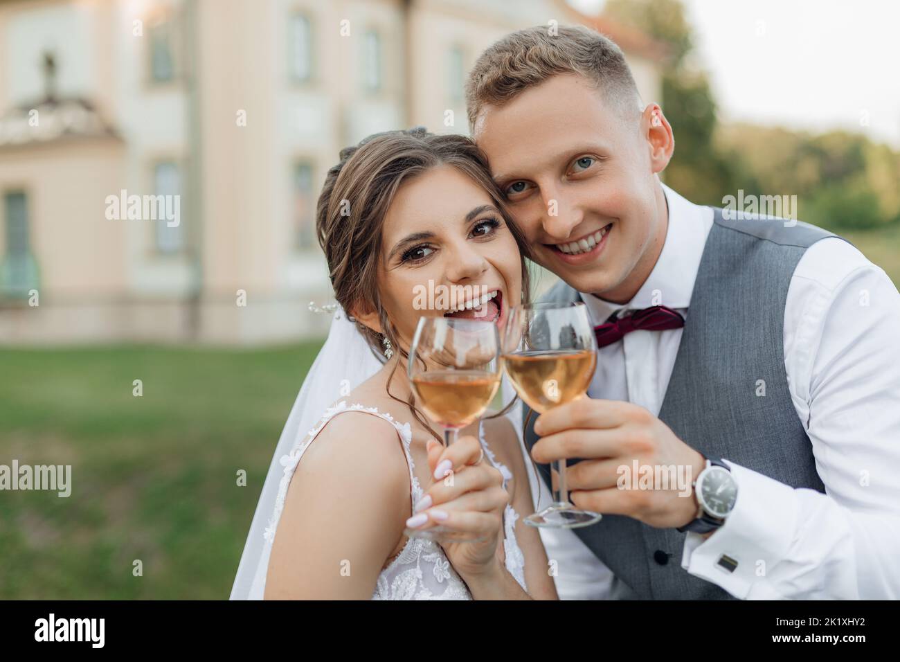 Cheerful Laughing Married Couple Of Bride In Wedding Dress And Groom In Suit Drinking And