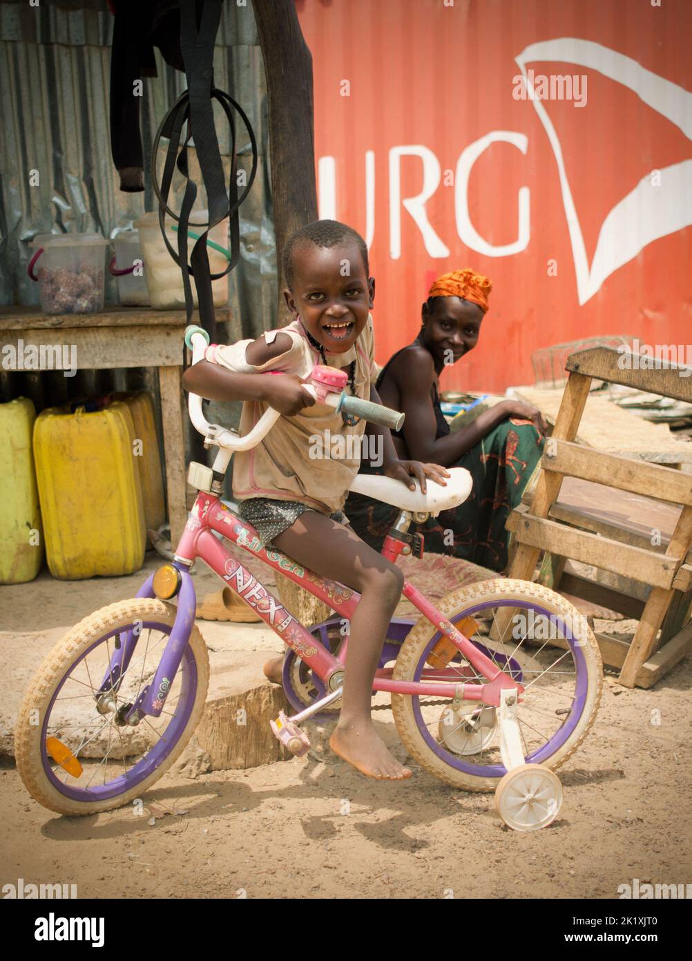 A portrait of a child riding a bicycle with her mother behind in Tokeh ...