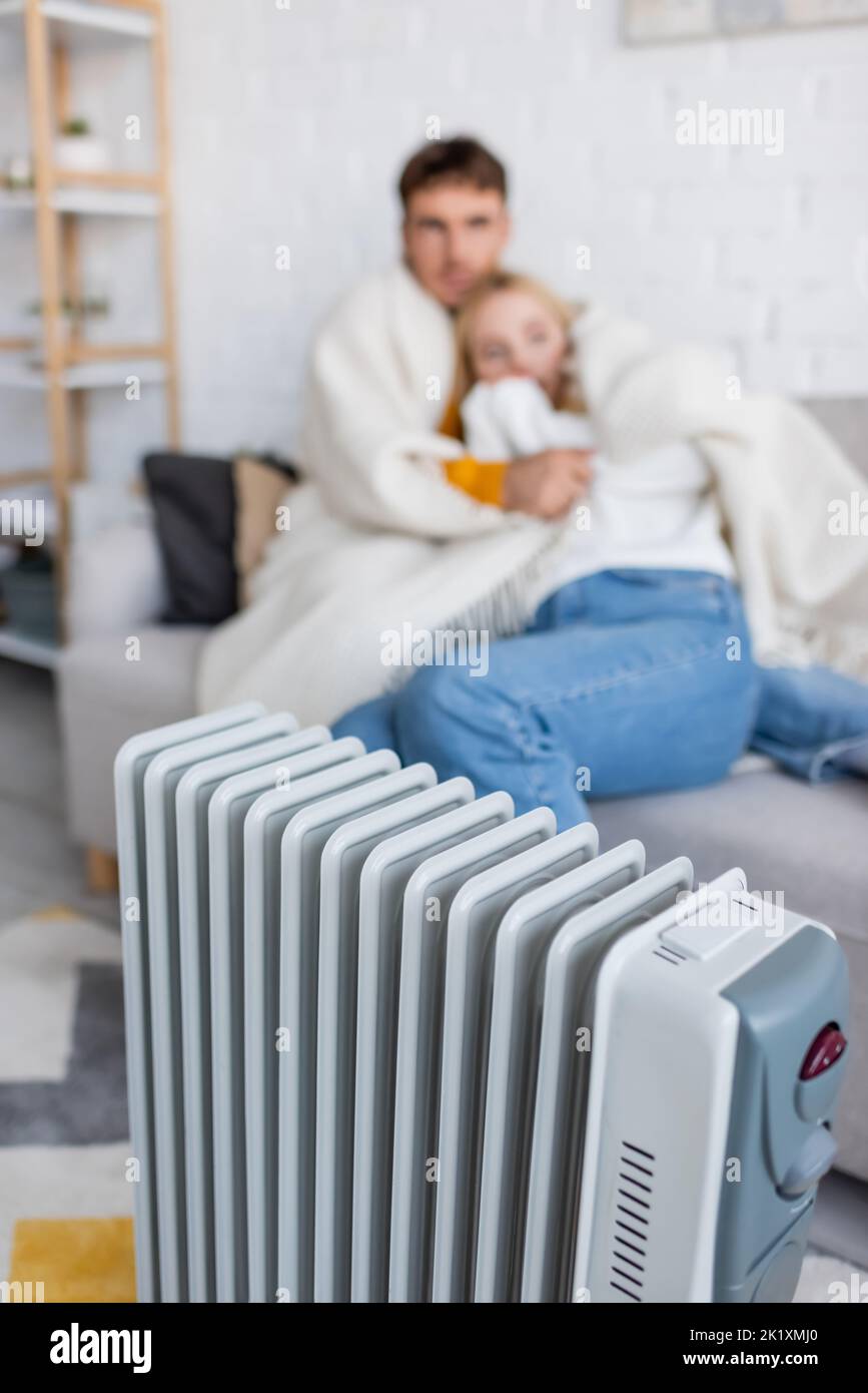 modern radiator heater near blurred couple hugging and sitting on couch ...