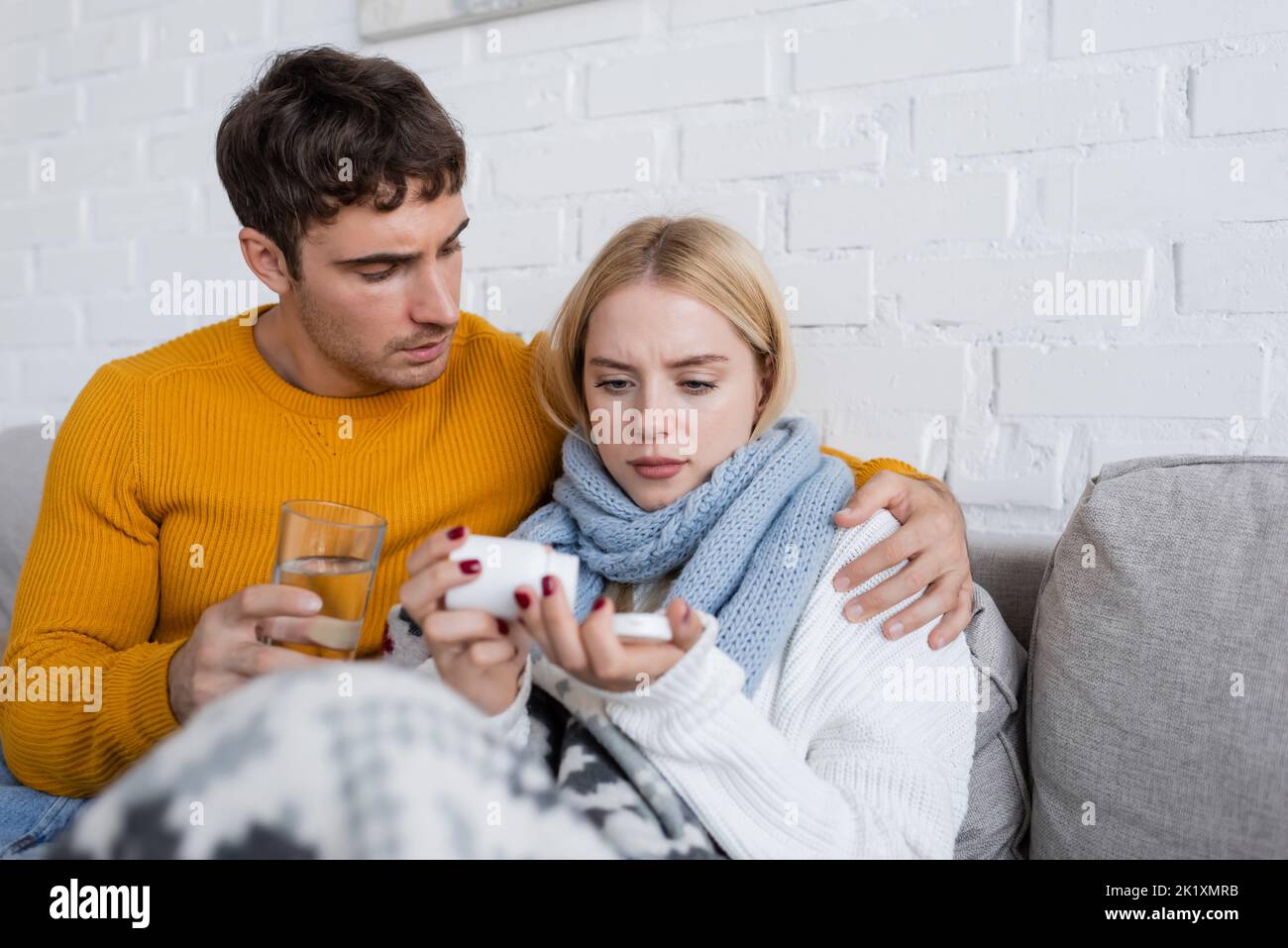 caring man holding glass with water and hugging sick girlfriend with ...