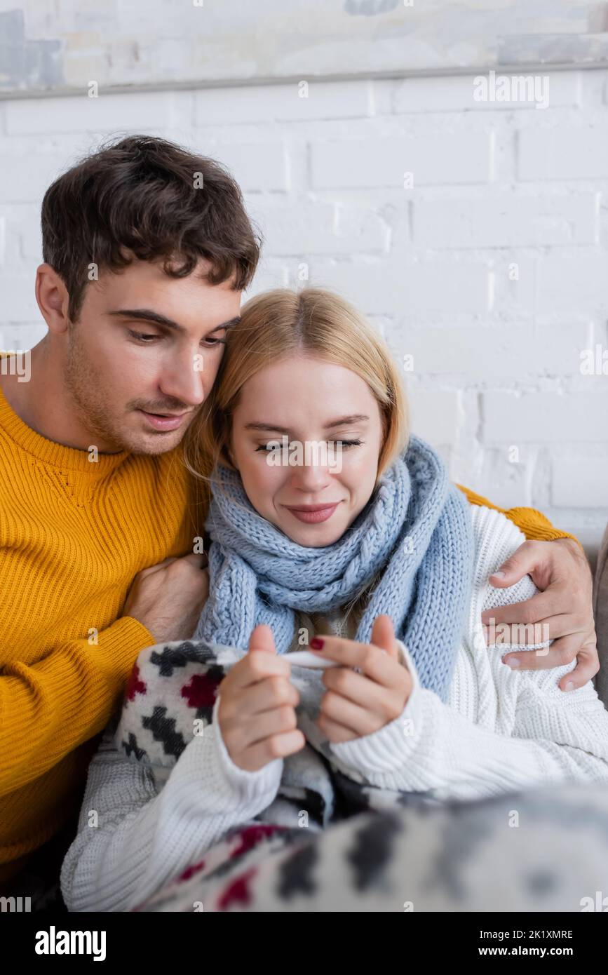 caring man hugging sick blonde woman with digital thermometer,stock ...