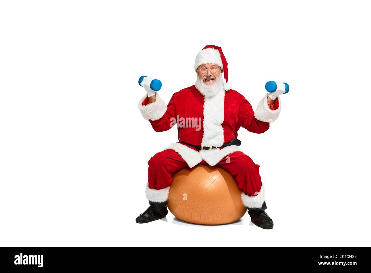 Portrait of senior man in image of Santa Claus sitting on exercise ball ...
