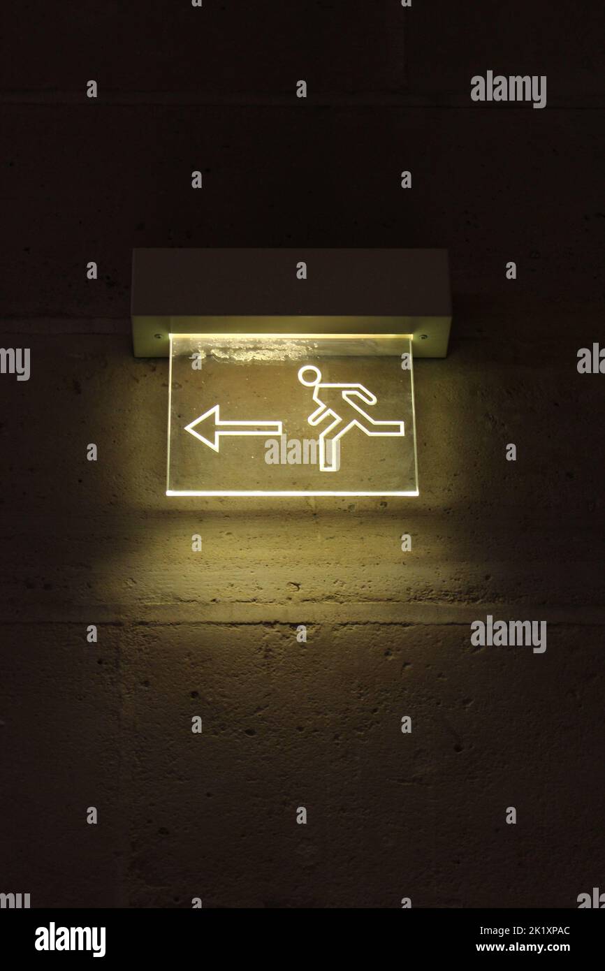 Illuminated pale yellow glass exit sign on the wall at night Stock ...