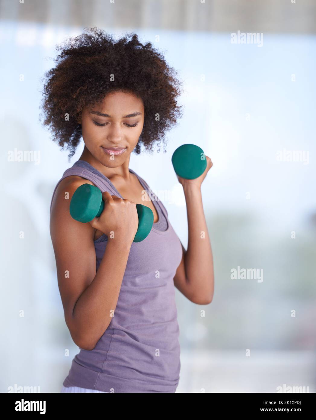 Working on her biceps. an attractive young woman working out with ...