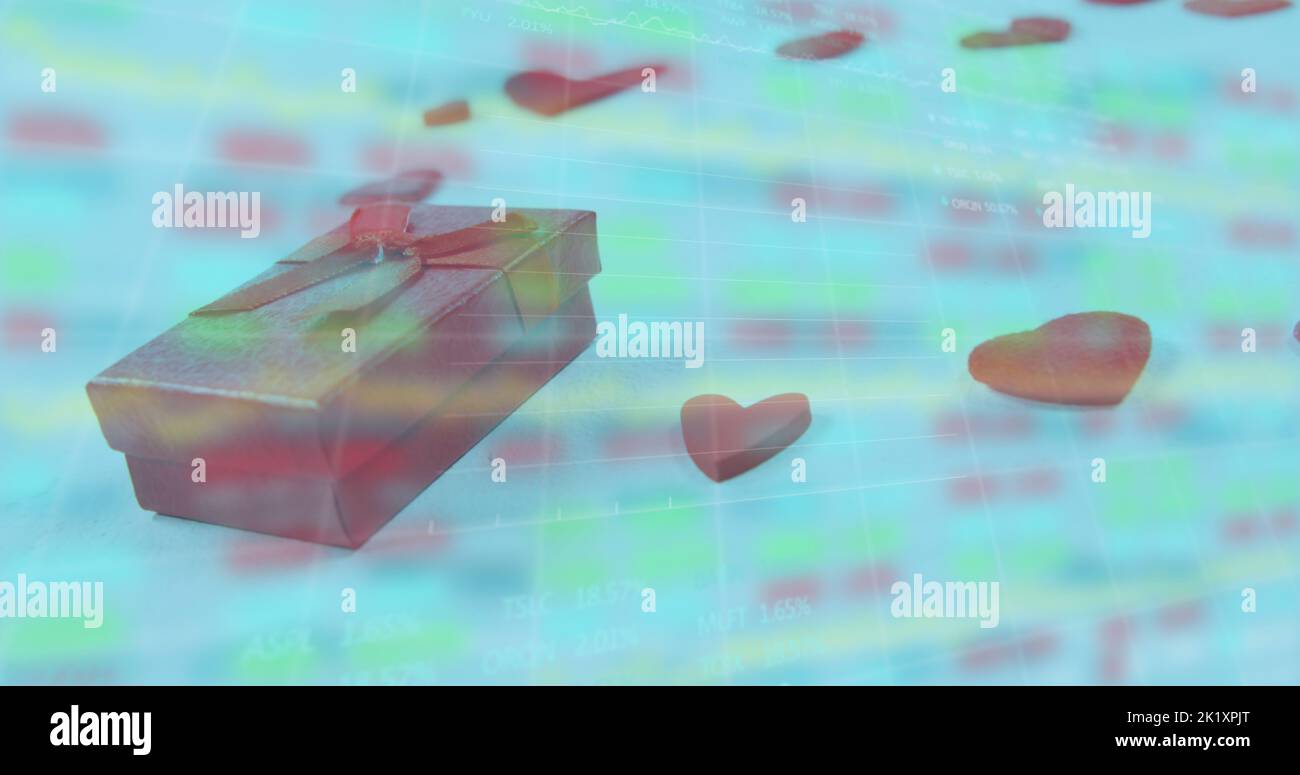 Image of gift box and heart shapes over moving graphs and trading board ...