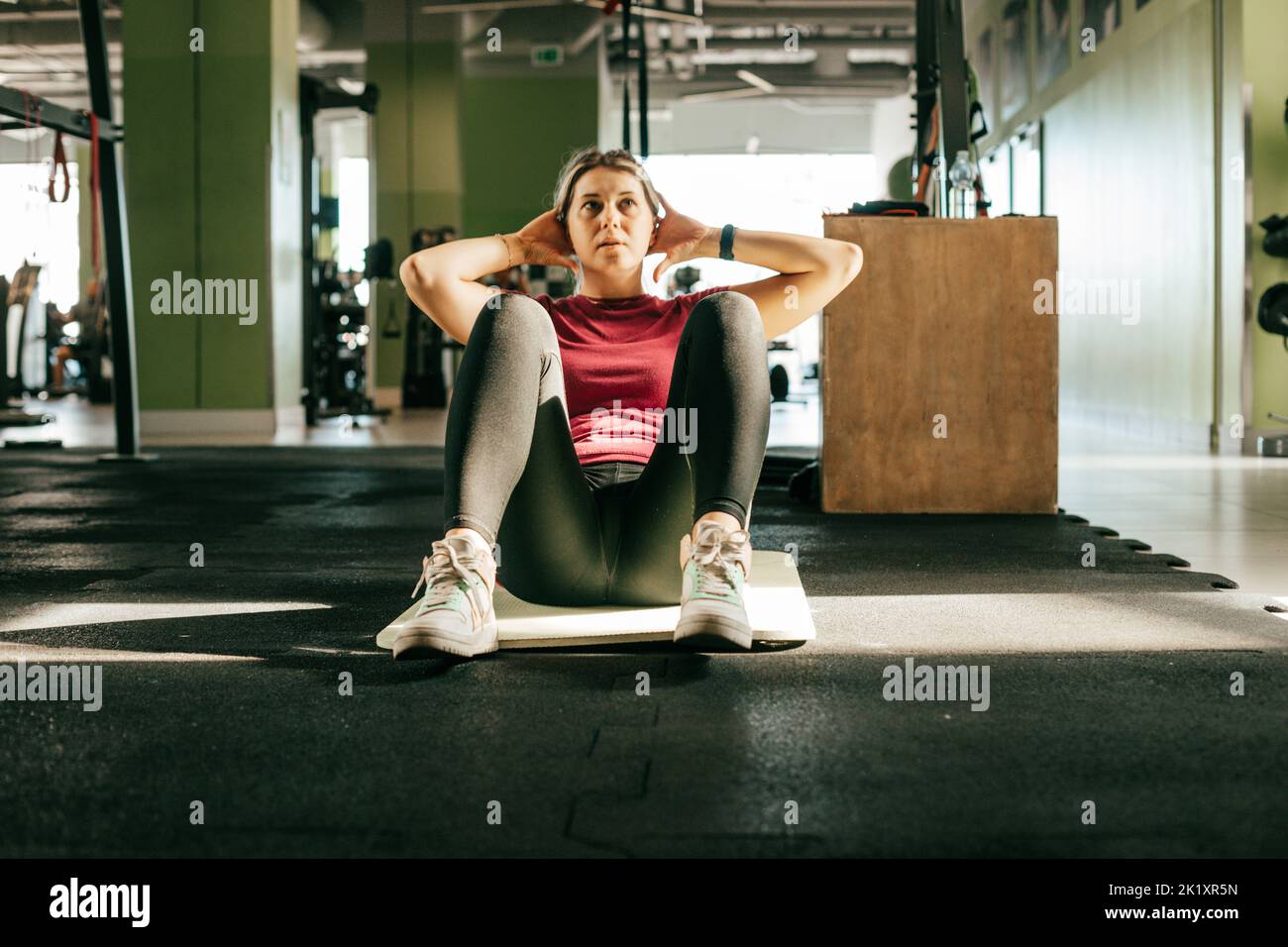Overweight girl pump press in fitness gym sitting on mat with hands on ...