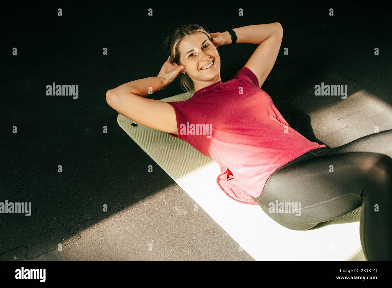 Joyful plus size girl with smile pump press in fitness gym lying on mat ...