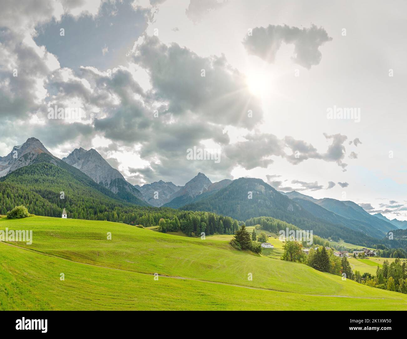 Church half-hidden behind a hill, mountain range with Piz Plavna Dadora ...