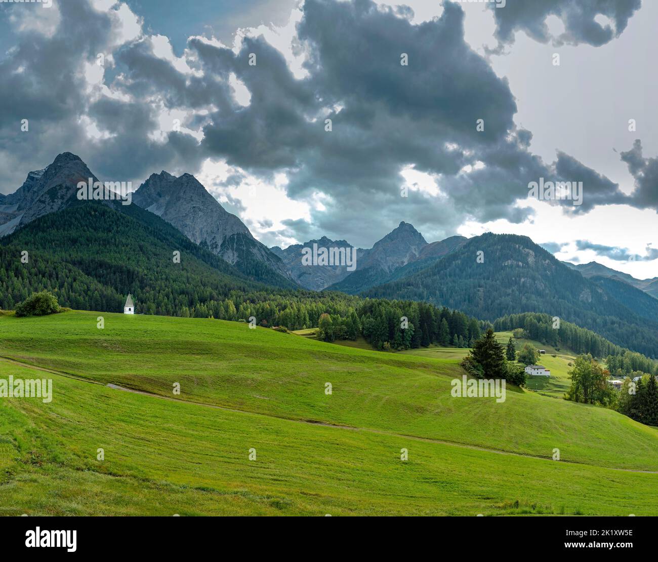 Church half-hidden behind a hill, mountain range with Piz Plavna Dadora ...