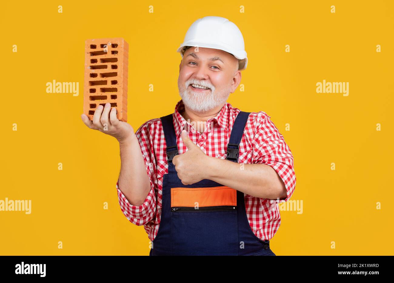 happy old man bricklayer in helmet on yellow background. thumb up Stock ...