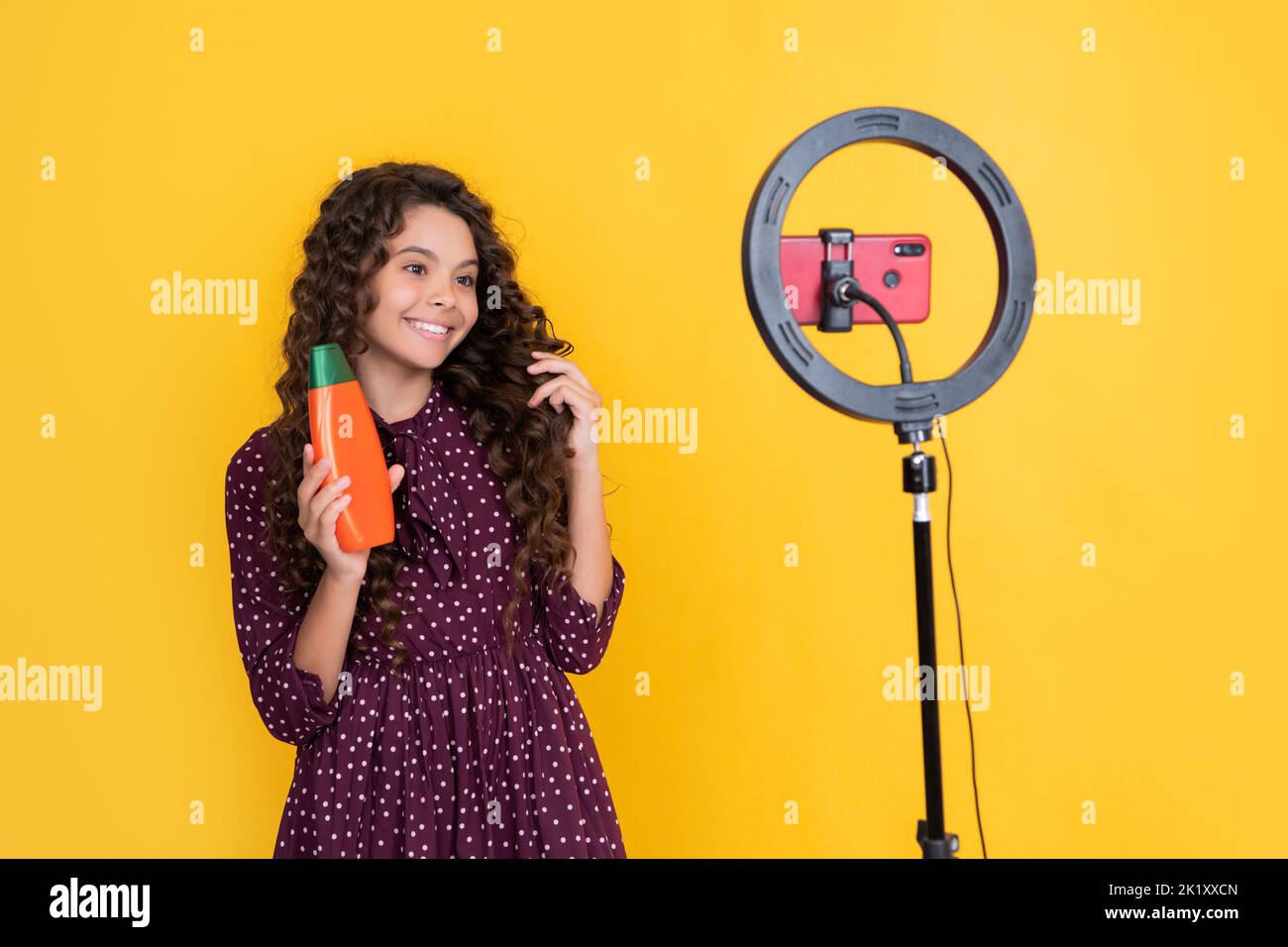 glad child with long curly hair making video for blog hold shampoo ...