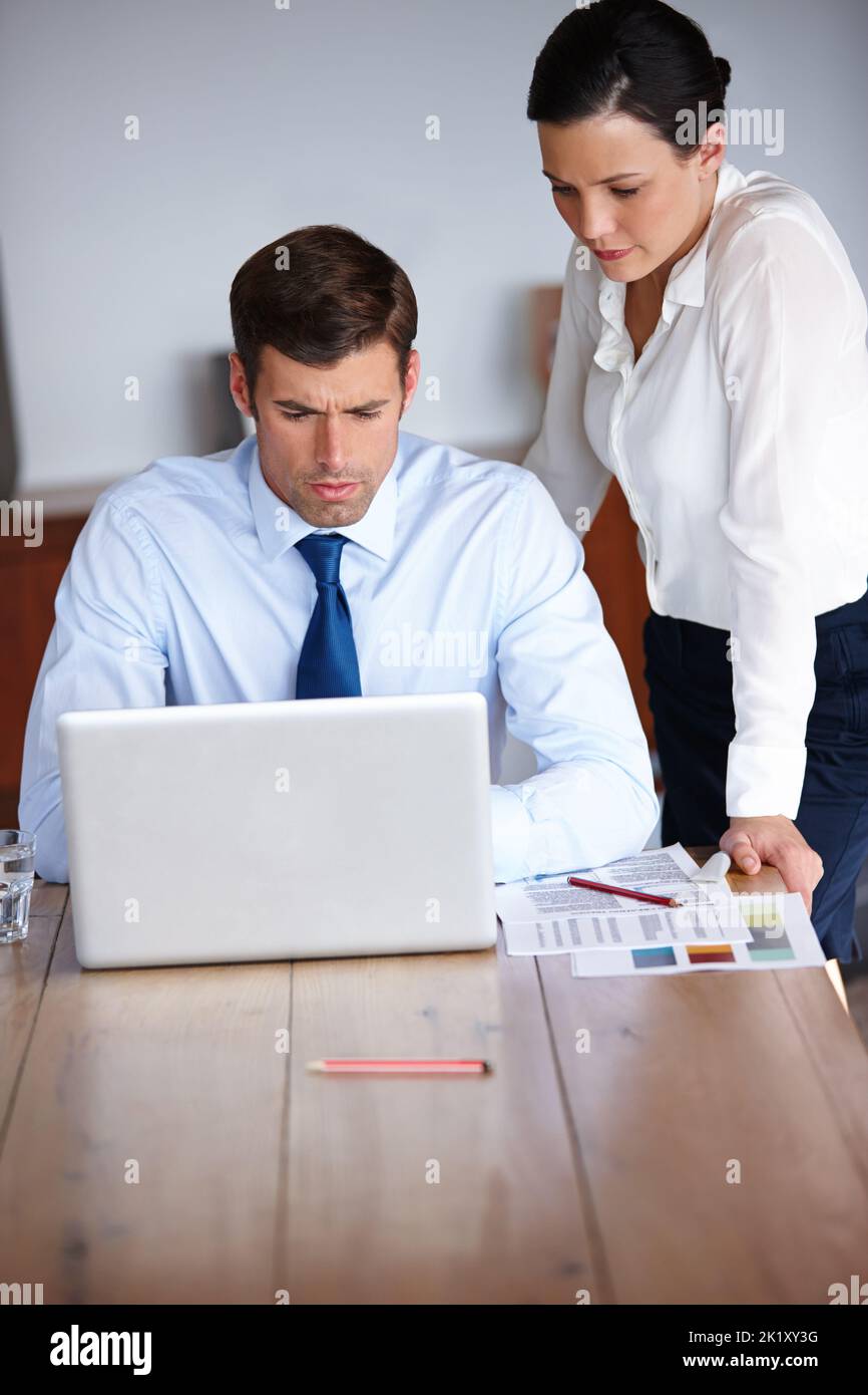 Showing the newbie the ropes. two business colleagues using a laptop in ...