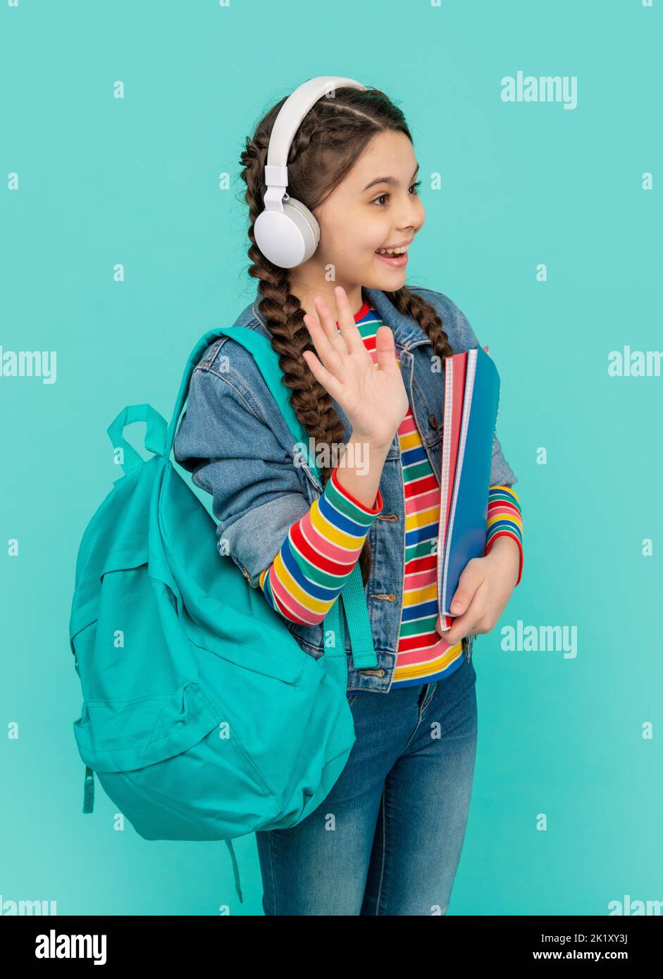 Happy teenage girl making hello gesture blue background, school. Back ...