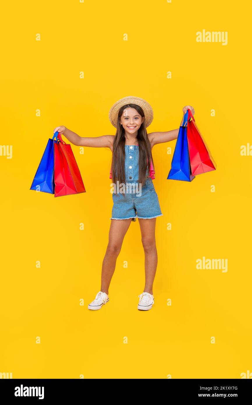 happy teen child shopaholic with shopping bags on yellow background ...