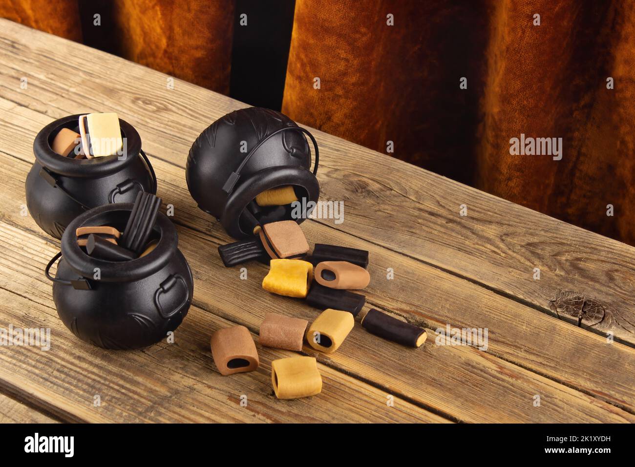 Three small toy witches' cauldrons with different candies stand on a ...