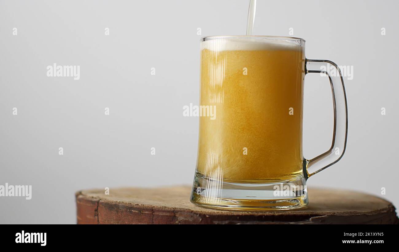 Beer is poured into a beer glass with a handle, a lot of bubbles and ...