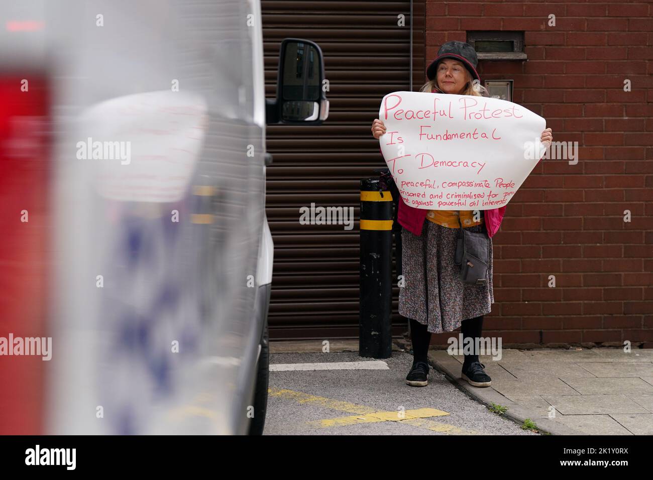 A supporter of Just Stop Oil protests at the vehicle entrance to ...