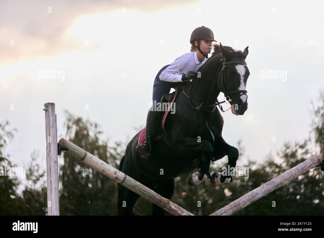 Jump over barrier. Young sportive girl, teen training at riding arena ...