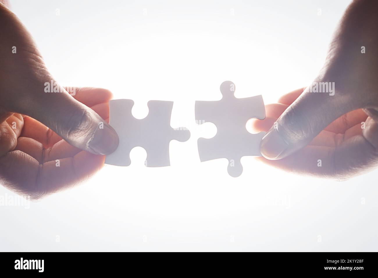 Making everything fit. hands holding two puzzle pieces Stock Photo - Alamy