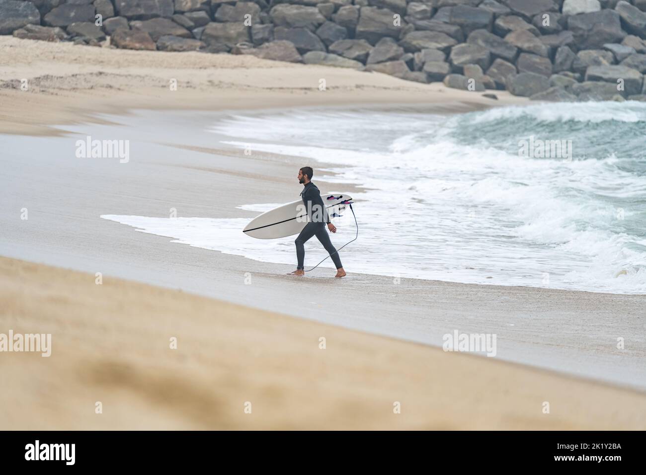 Side view of man with surfboard on beach. Side view of surfer in ...