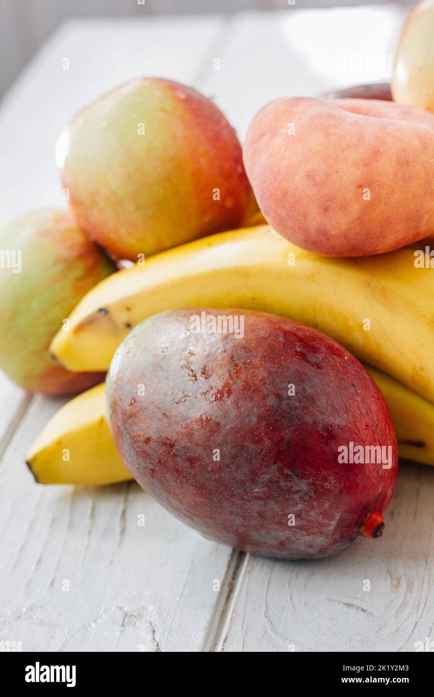 Fresh and ripes fruits - banana, mango, peach and apples on the table ...