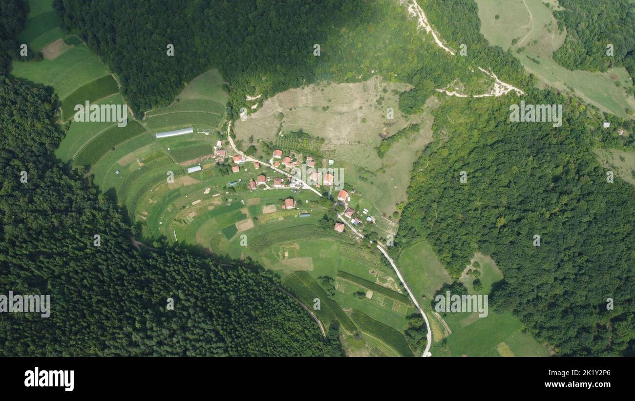 An aerial top down view of a Bosnian village surrounded by forests and ...