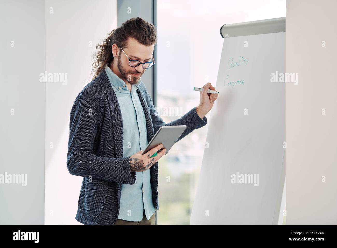A young teacher writes on board lectures for students in a classroom ...