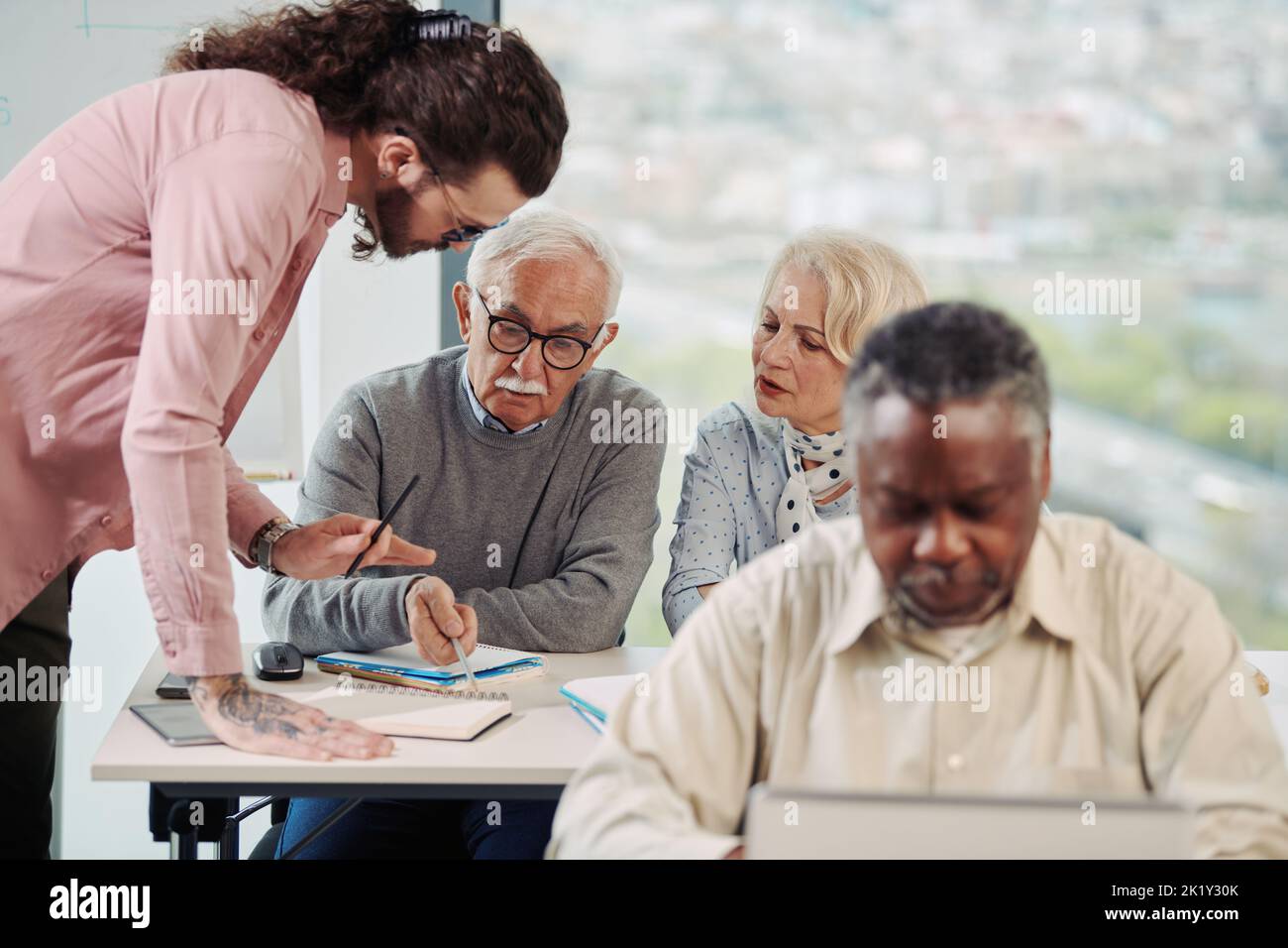 A multiracial group of senior students is talking with a young educator ...