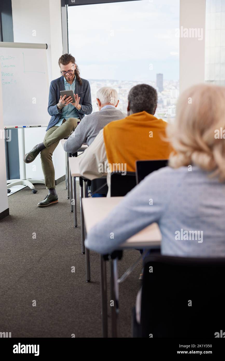 Young educator teaching a multicultural group of senior students in the ...