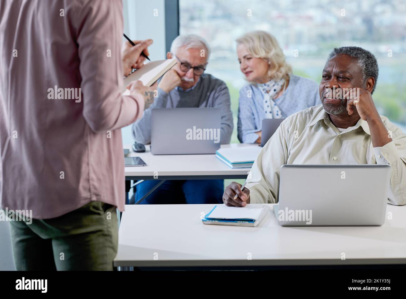 Young hipster educator teaching a multicultural group of senior ...