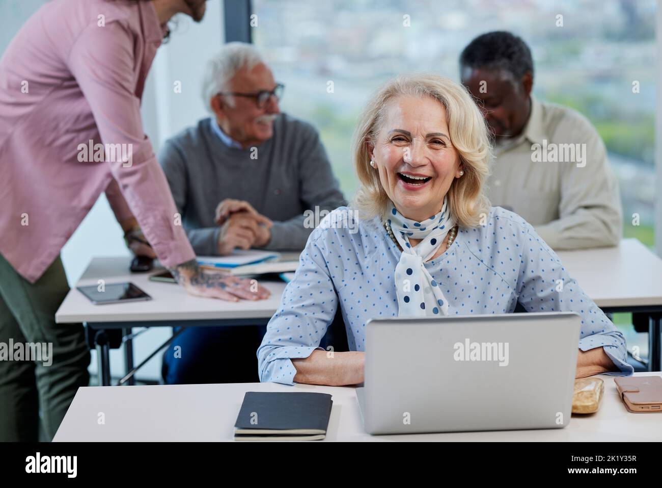 A happy female senior student sits in a classroom and does an ...