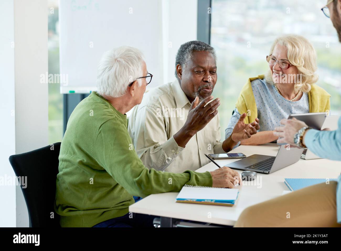 Multicultural group of senior students asking questions their tutor who ...