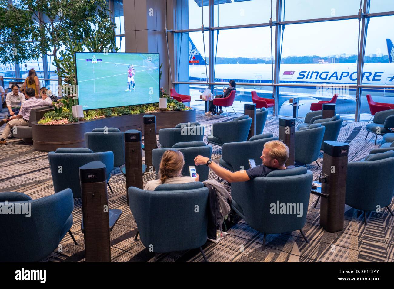 Passengers watching TV in lounge while waiting for flight. Changi ...