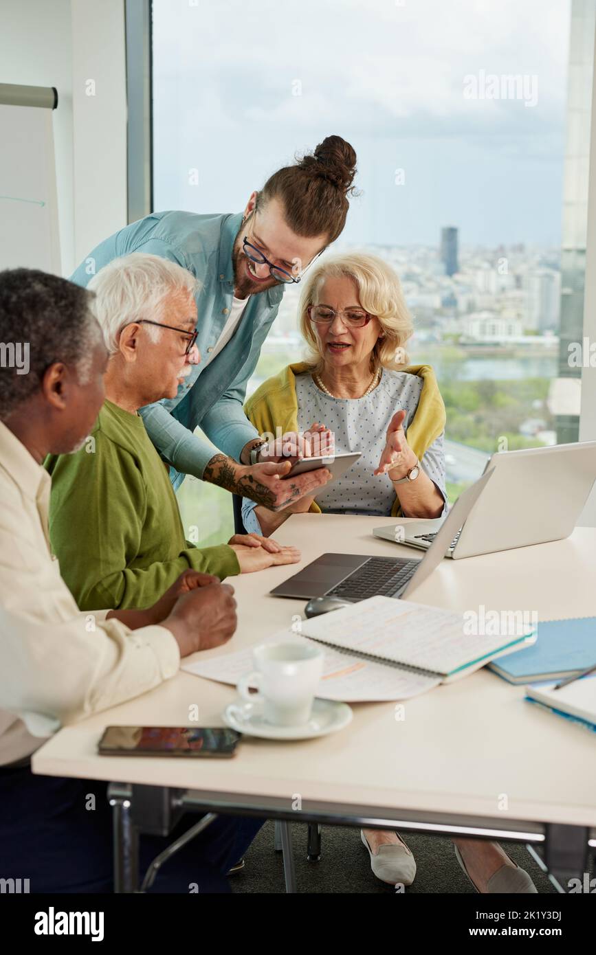 A hipster educator is showing a lesson on the tablet to a multicultural ...