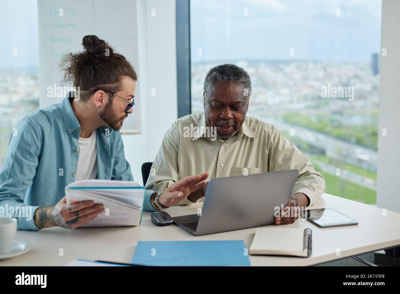 A young teacher explaining to senior student how do computer ...
