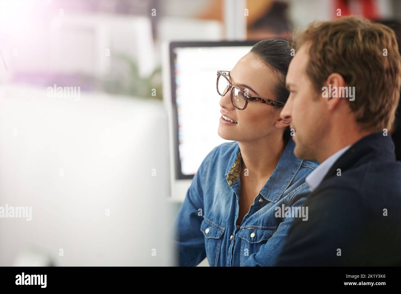 Getting help from a colleague. two colleagues sitting in front of a ...