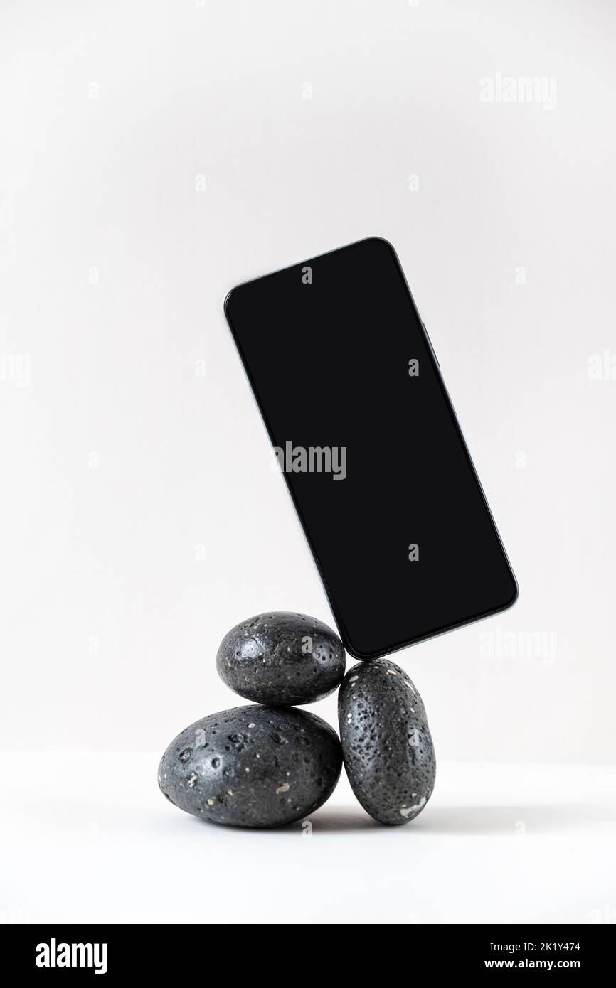 Composition of modern mobile phone with empty screen balancing on black ...