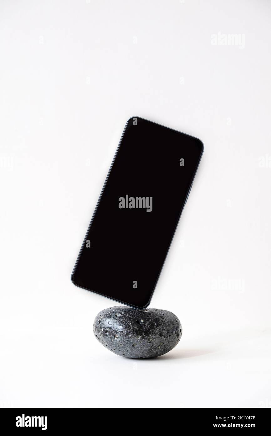 Composition of modern mobile phone with empty screen balancing on black ...
