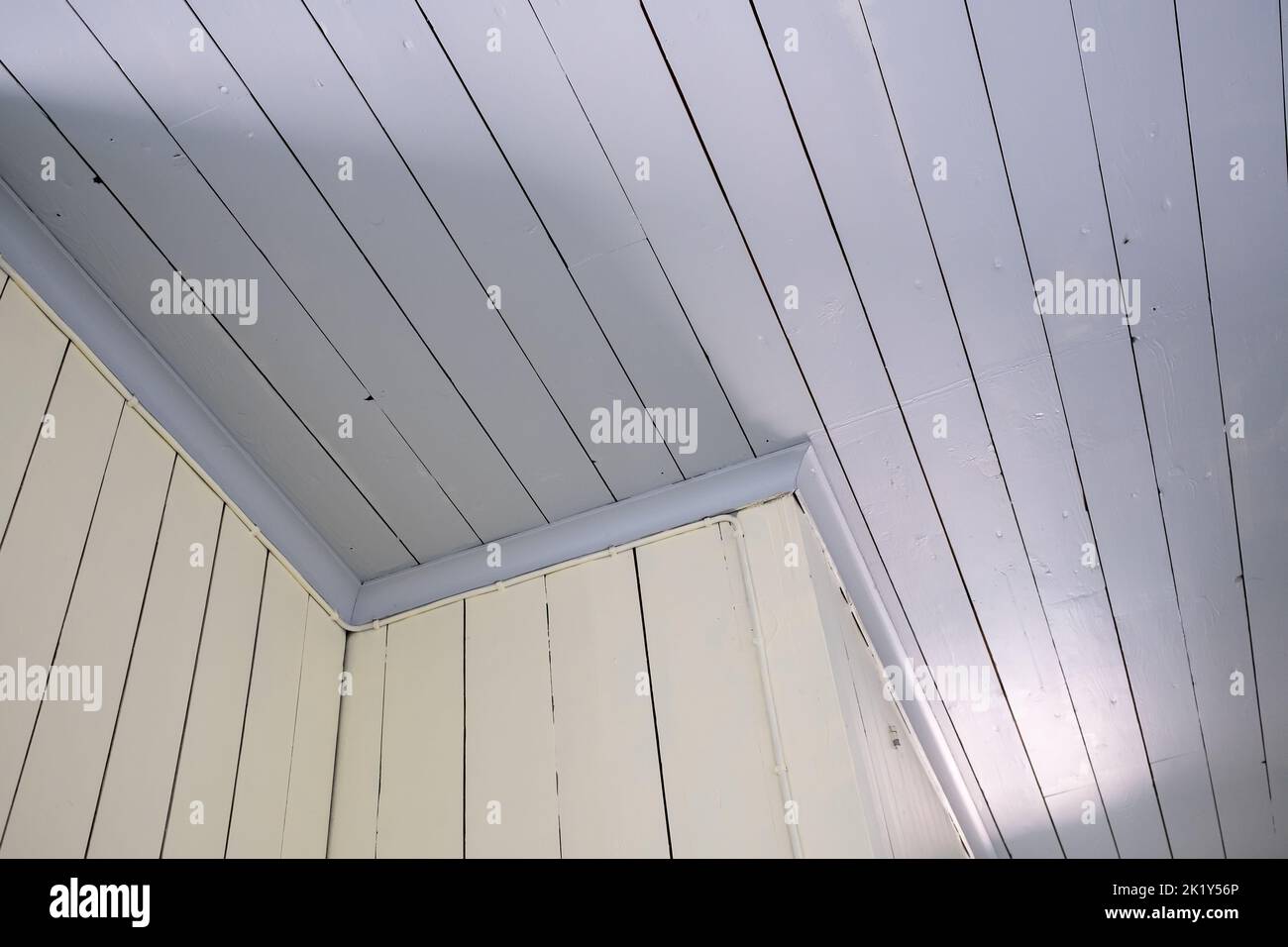 Ceiling and walls are made of wooden planks painted in white and grey ...