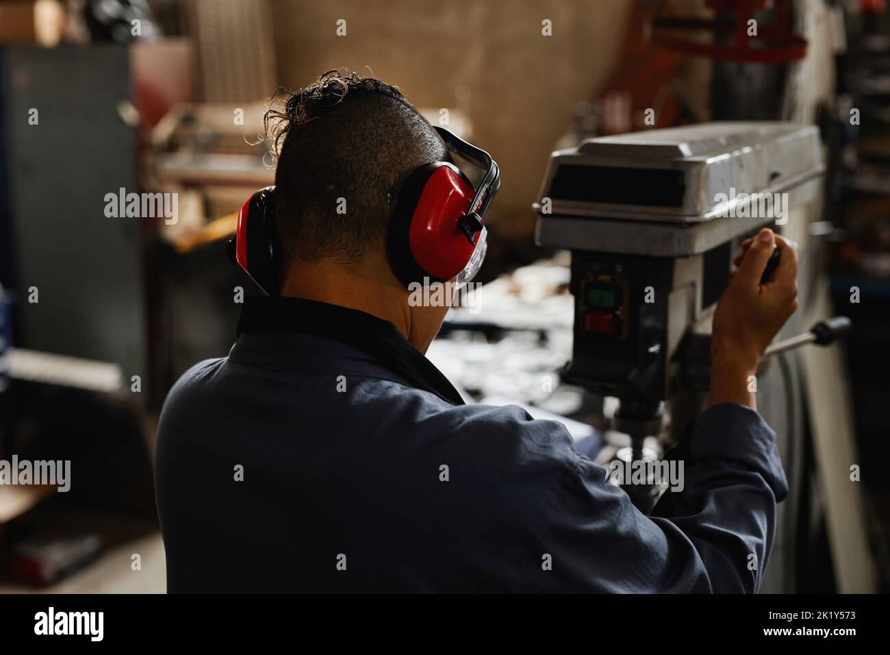 Back view of worker operating machine units in industrial workshop and ...