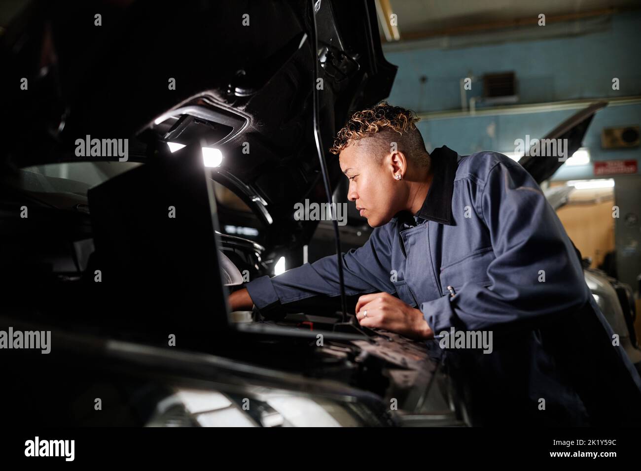 Side view portrait of female mechanic repairing truck engine in garage ...
