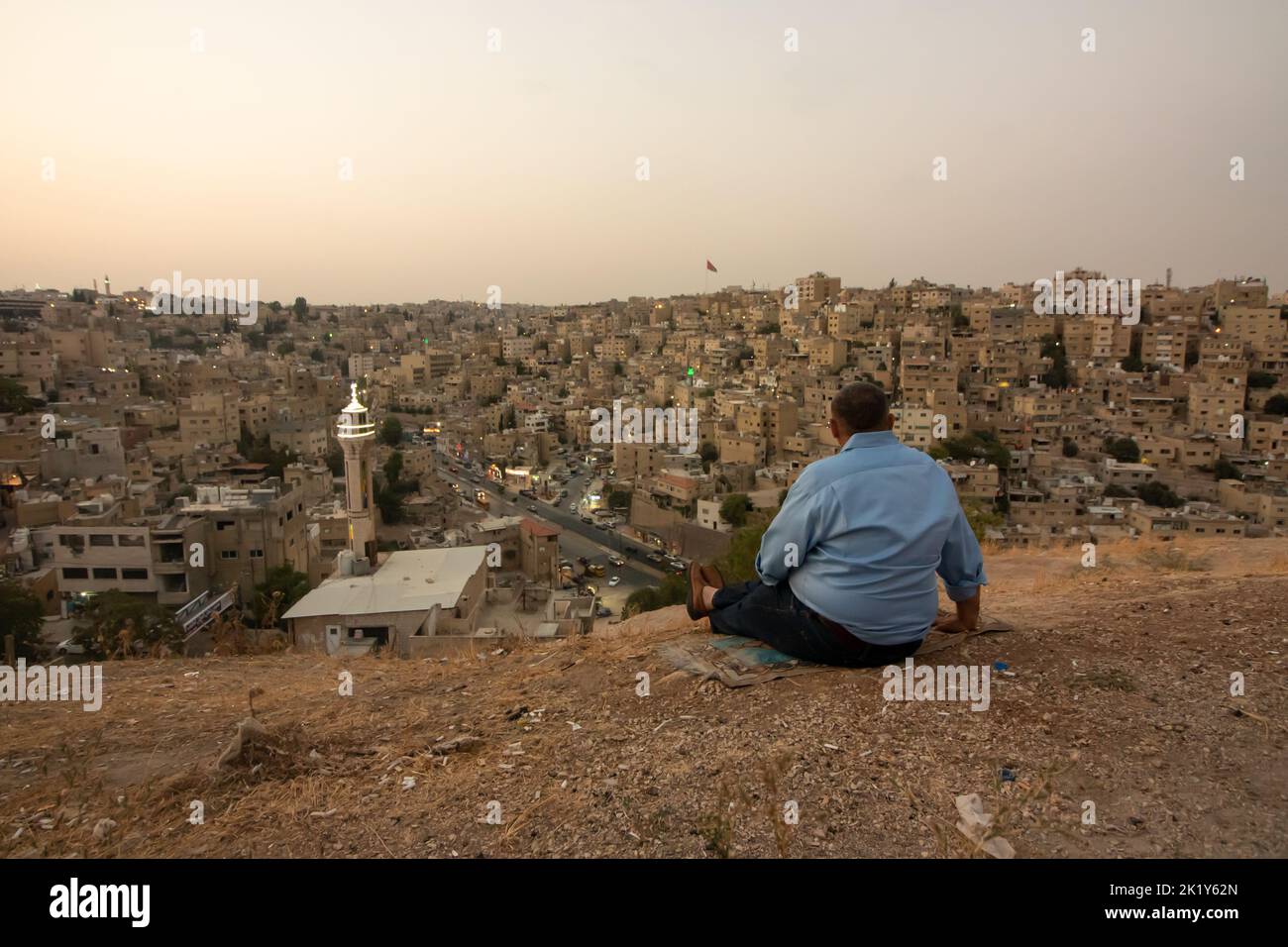 At sunset, a man looks Amman from the Citadel, built on top of the hill ...