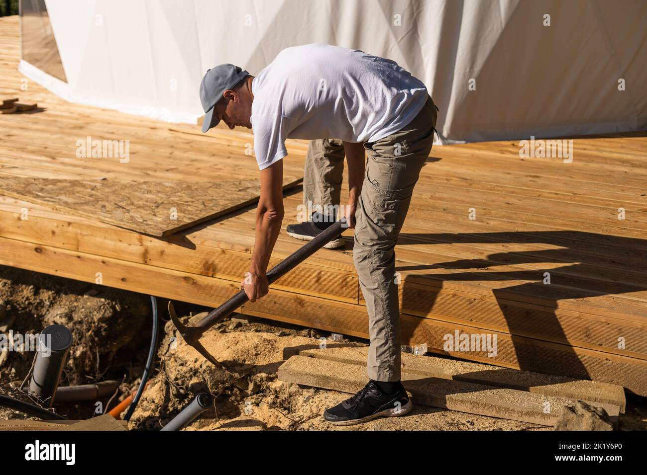 Young manual worker standing at stack with thin wooden boards during ...